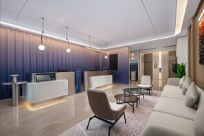 Uma área de recepção moderna com balcão de mármore, assentos e televisão de tela plana.