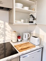 Uma cozinha equipada com fogão embutido, torradeira, chaleira e cafeteira.