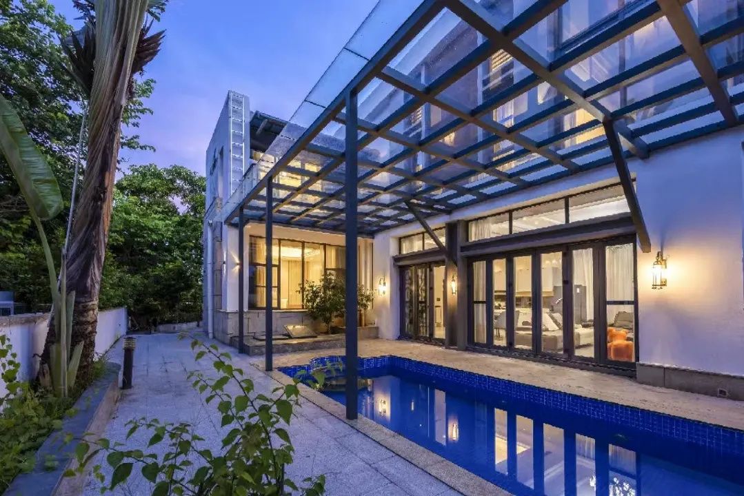 Uma casa moderna com um alpendre envidraçado e piscina.