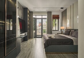 Quarto de hotel moderno com uma cama grande, televisão e varanda com vista para edifícios.