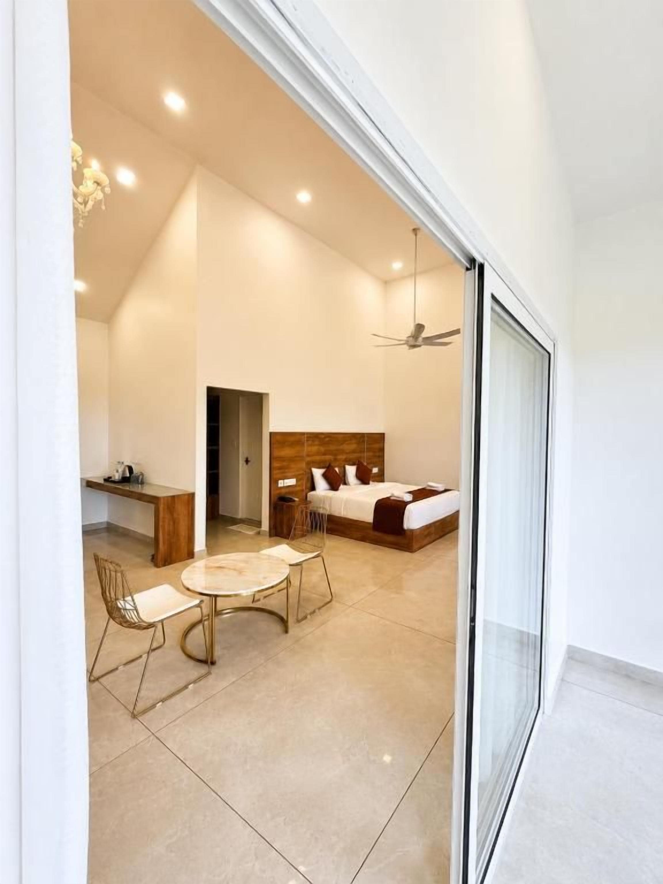 Quarto moderno com cama, mesa de cabeceira e área de trabalho com cadeira.