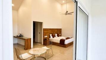 Quarto moderno com cama, mesa de cabeceira e área de trabalho com cadeira.