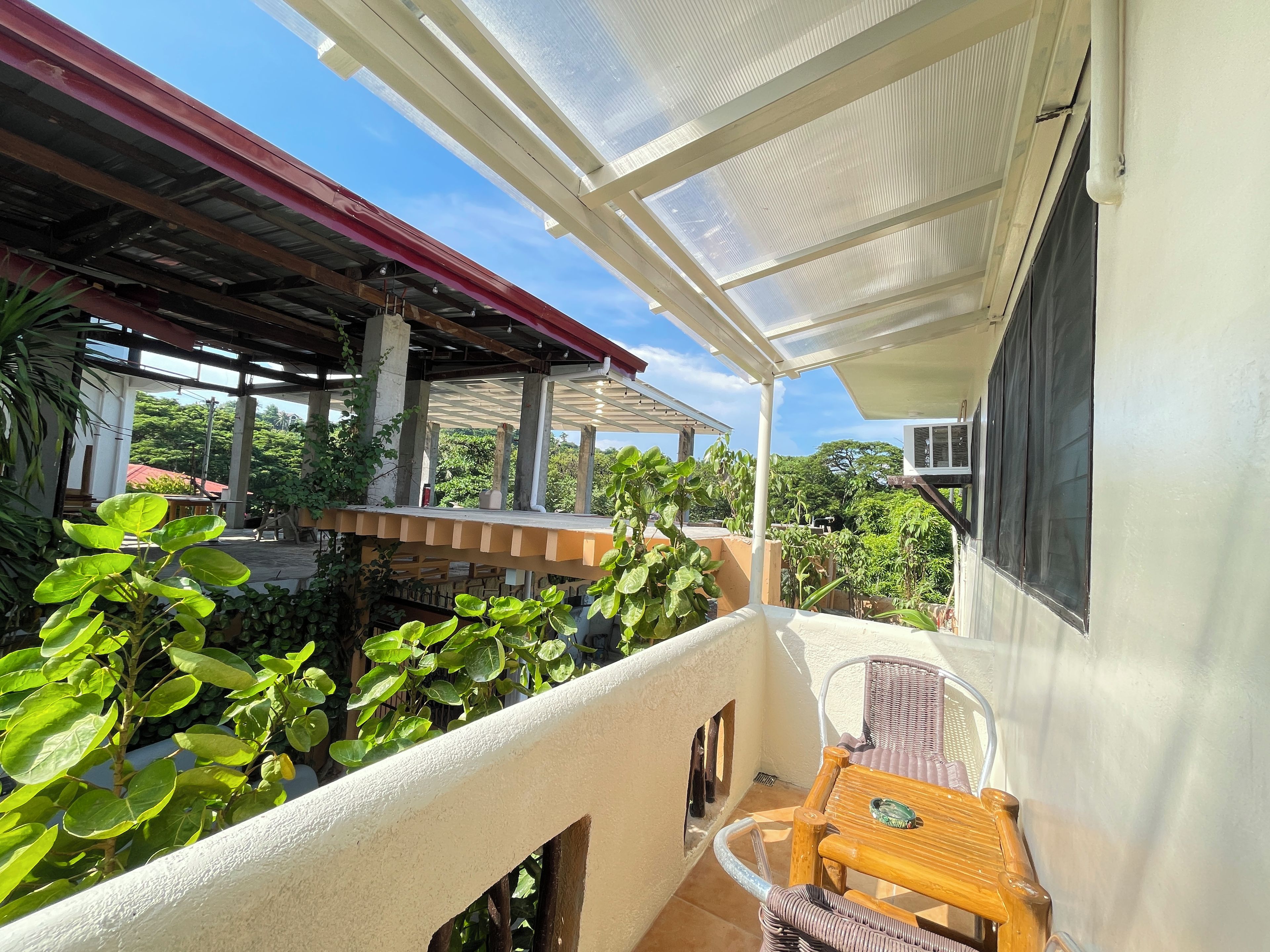 Varanda com vista para o verde, uma mesa de madeira e guarda-corpo branco.
