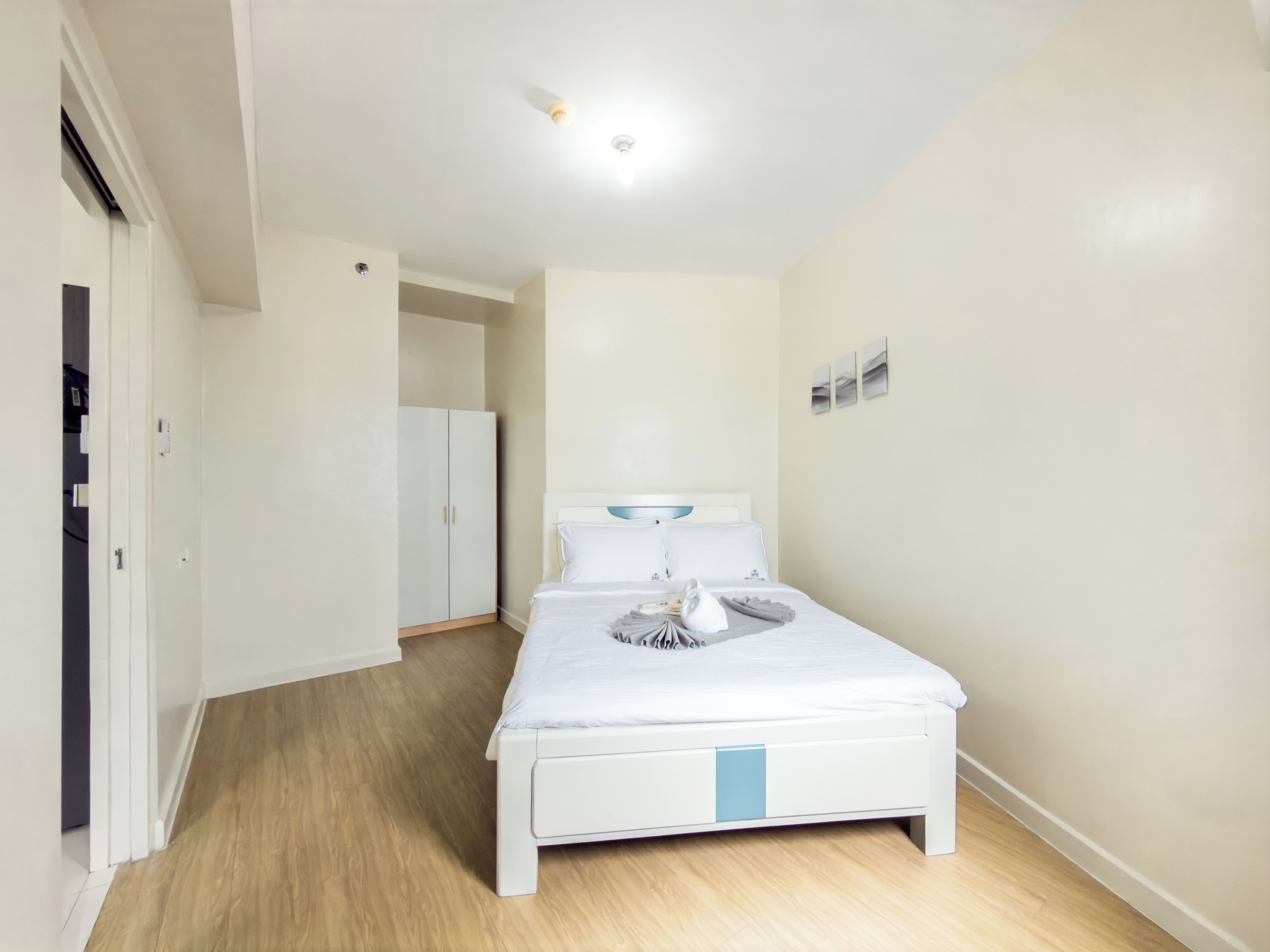 Quarto de hotel com cama, guarda-roupa e porta que dá para outro espaço.