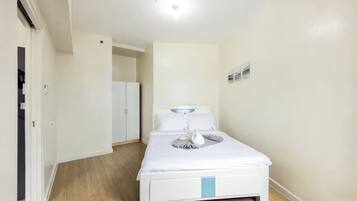 Quarto de hotel com cama, guarda-roupa e porta que dá para outro espaço.