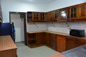 Cozinha com armários de madeira, micro-ondas e geladeira.