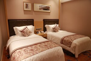 Quarto de hotel com duas camas, cada uma com cabeceira, mesa de cabeceira com telefone e relógio fixado na parede.