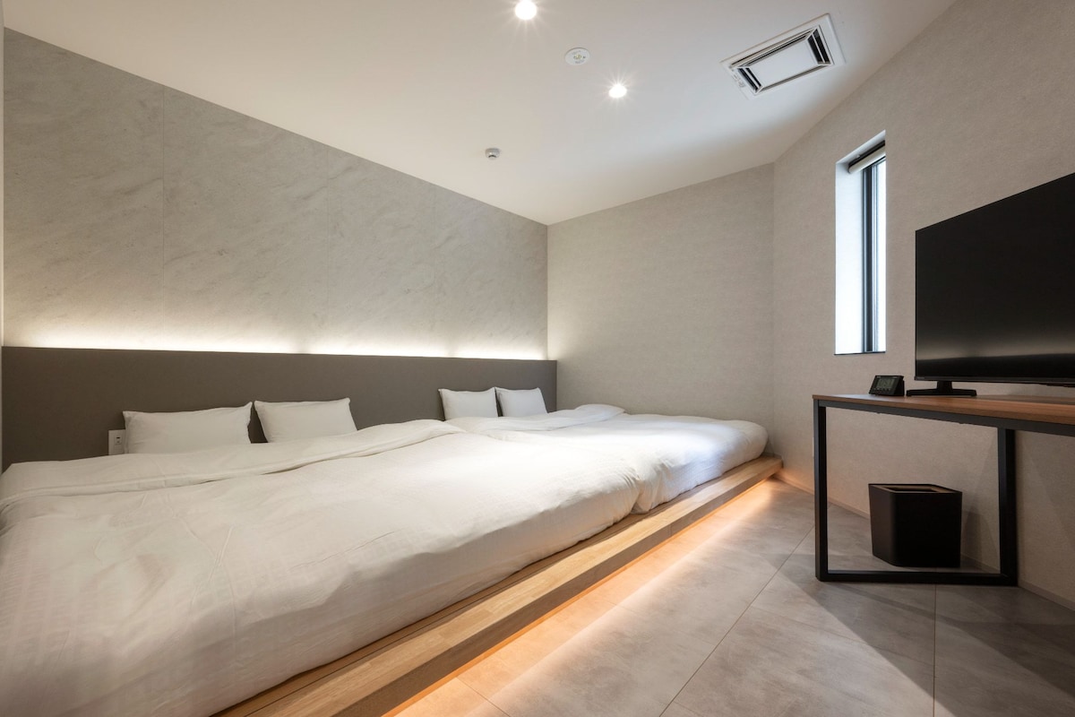 Quarto de hotel moderno com uma cama grande, televisão e janela.