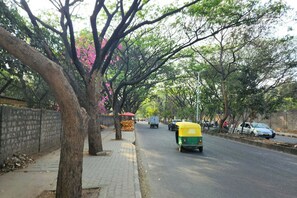 Rua arborizada com calçada e veículos estacionados.
