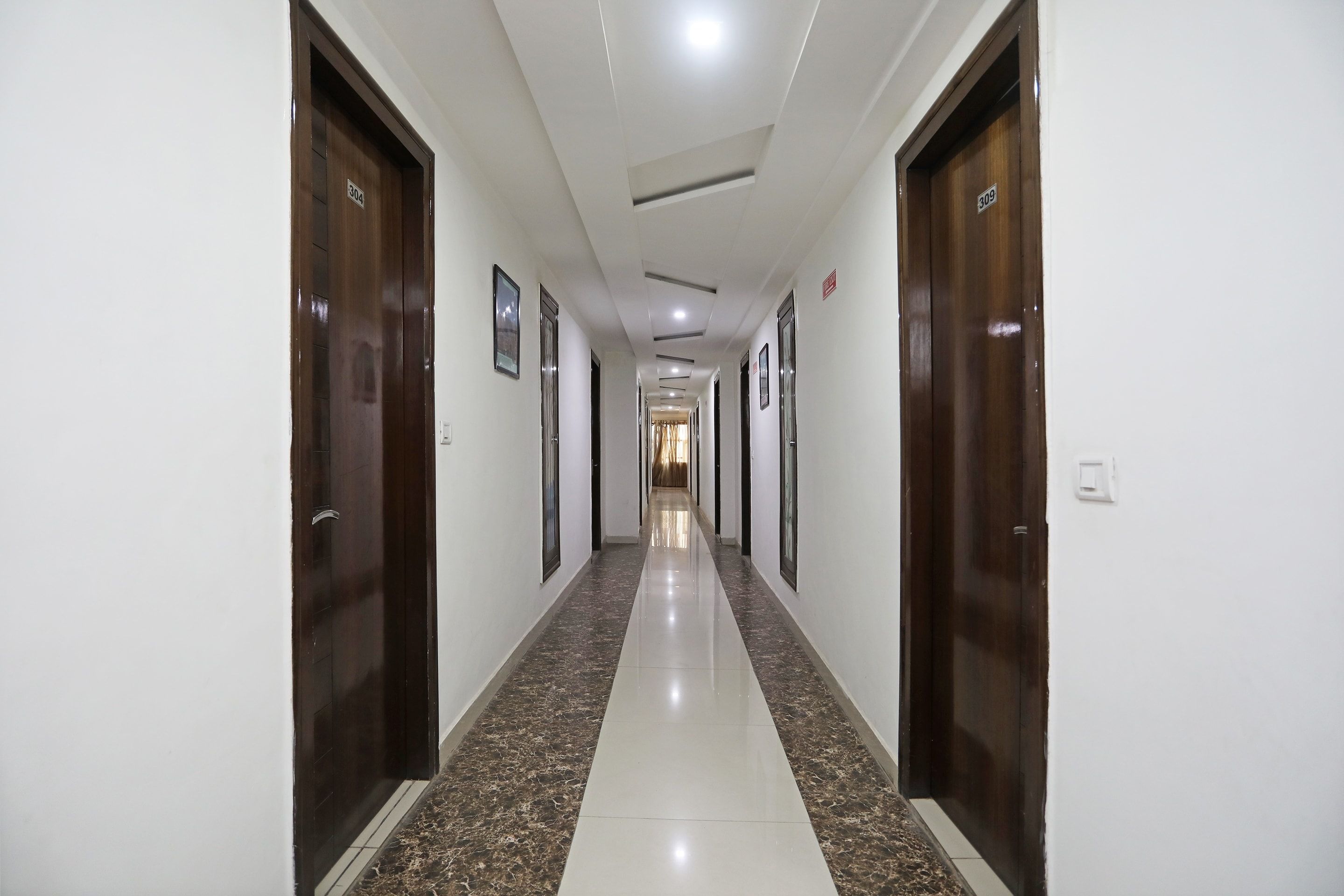 Corredor de hotel com portas numeradas 304 e 309, dando acesso aos quartos.