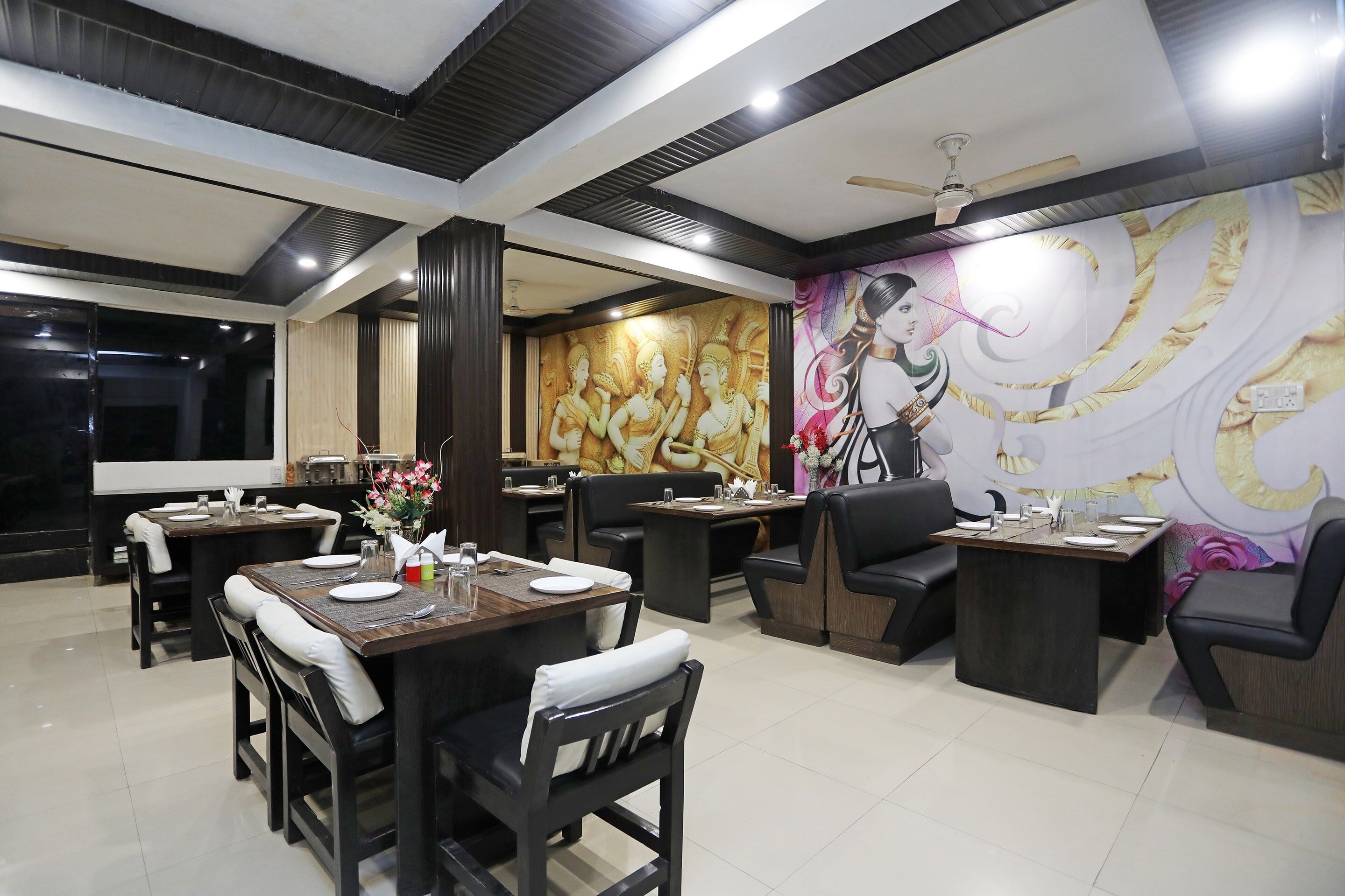 Restaurante com várias mesas para refeições, cadeiras estofadas pretas e um ventilador de teto.