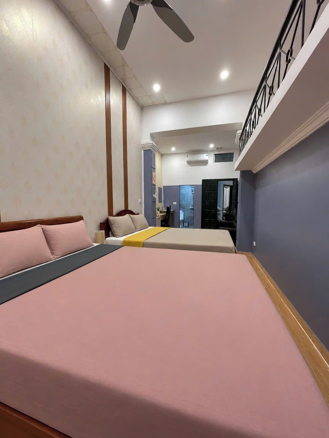Quarto com uma cama grande, um ventilador de teto e uma escada que dá para um andar superior.