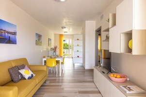 Uma sala de estar moderna com sofá, área de refeições e cozinha.