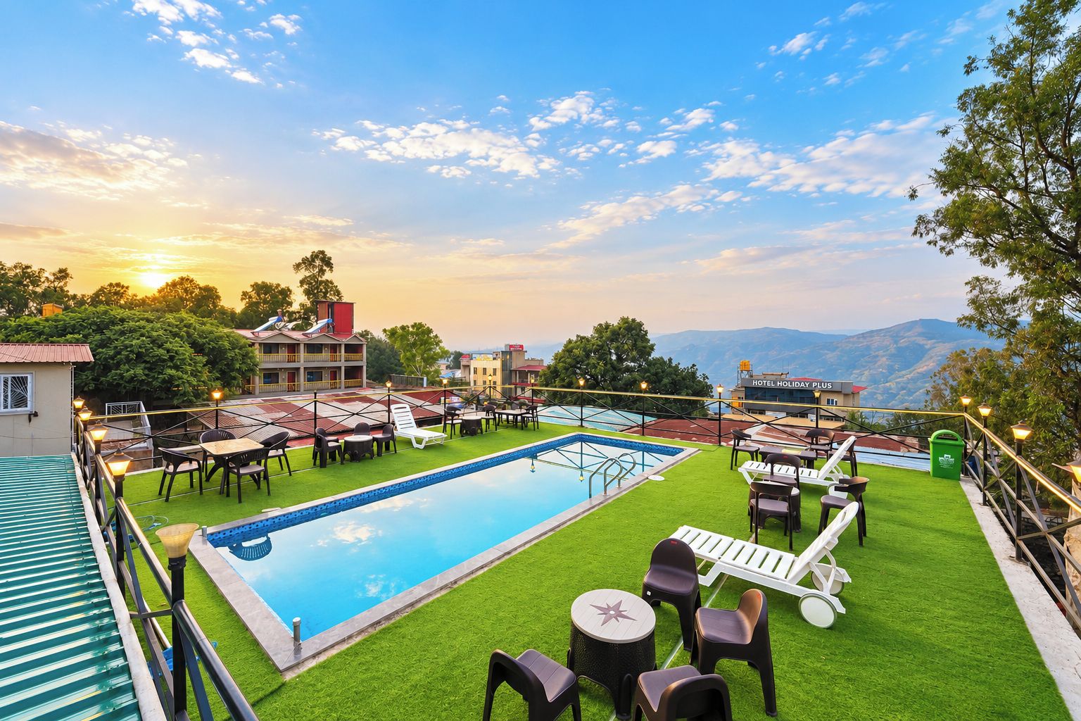 Área de piscina no terraço com vista para montanhas, rodeada por espreguiçadeiras e mesas.