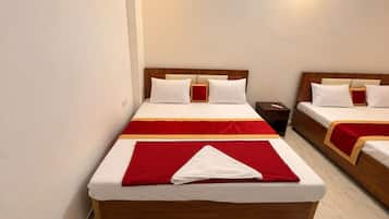 Quarto de hotel com duas camas, cada uma com cabeceira de madeira, roupa de cama branca e detalhes em vermelho.