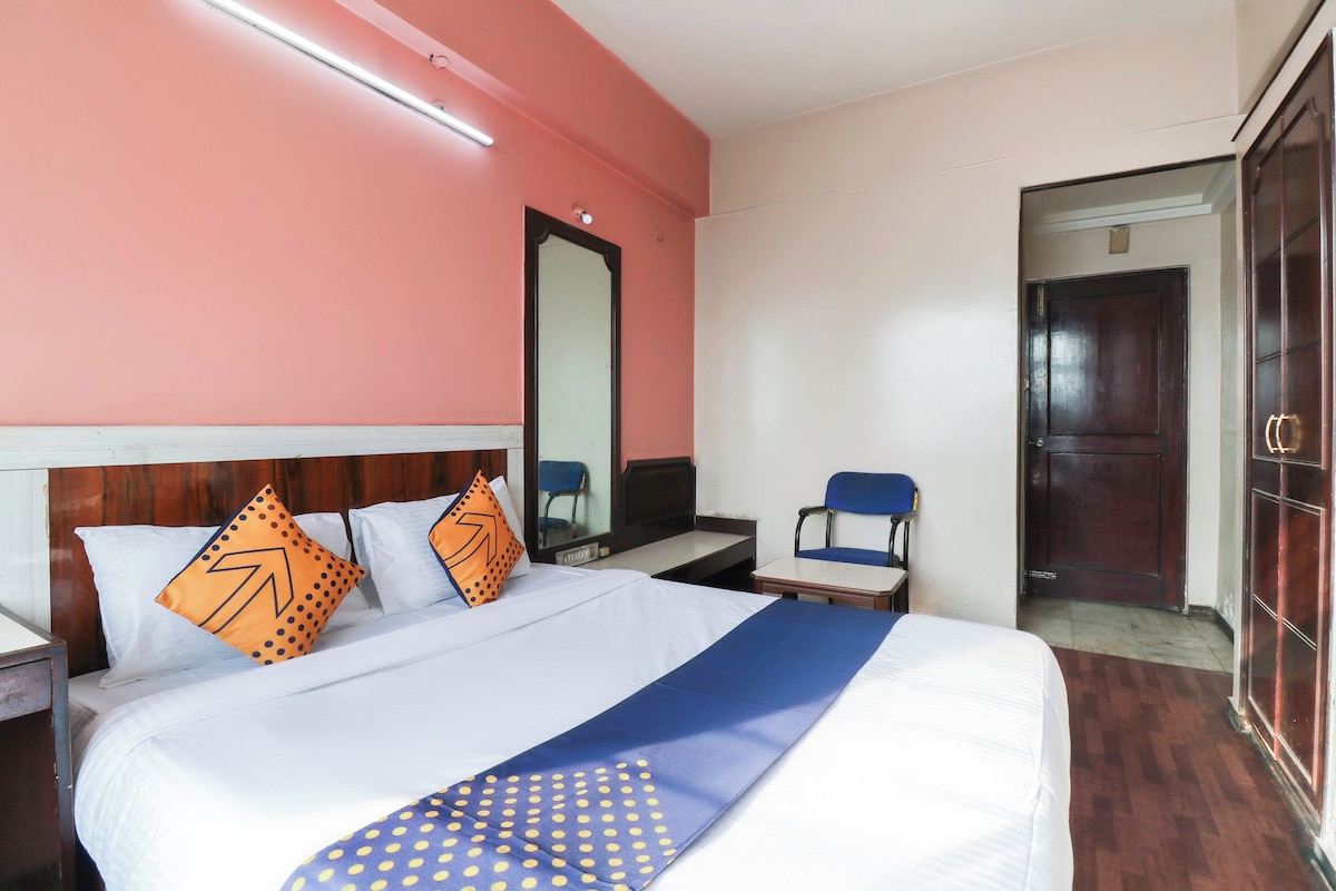 Quarto de hotel com cama, cadeira, escrivaninha e guarda-roupa.