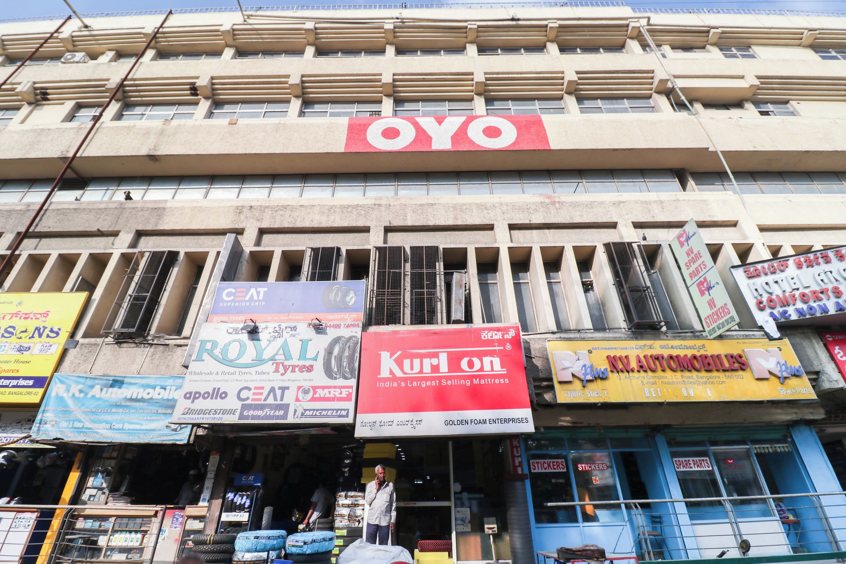Um edifício com várias placas comerciais, incluindo uma placa grande da 'OYO'.