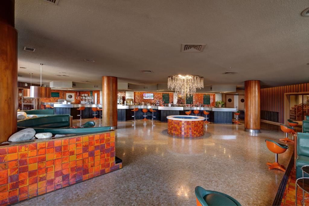 Um hall amplo com bar central, áreas de estar e uma fonte decorativa.