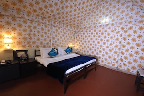 Quarto de hotel com cama, duas luminárias de cabeceira, mesa de cabeceira e uma cadeira.