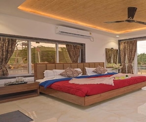 Quarto com cama grande, ventilador de teto e janela com cortinas.