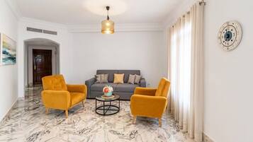 Sala de estar com sofá, duas poltronas, mesa de centro e relógio de parede.