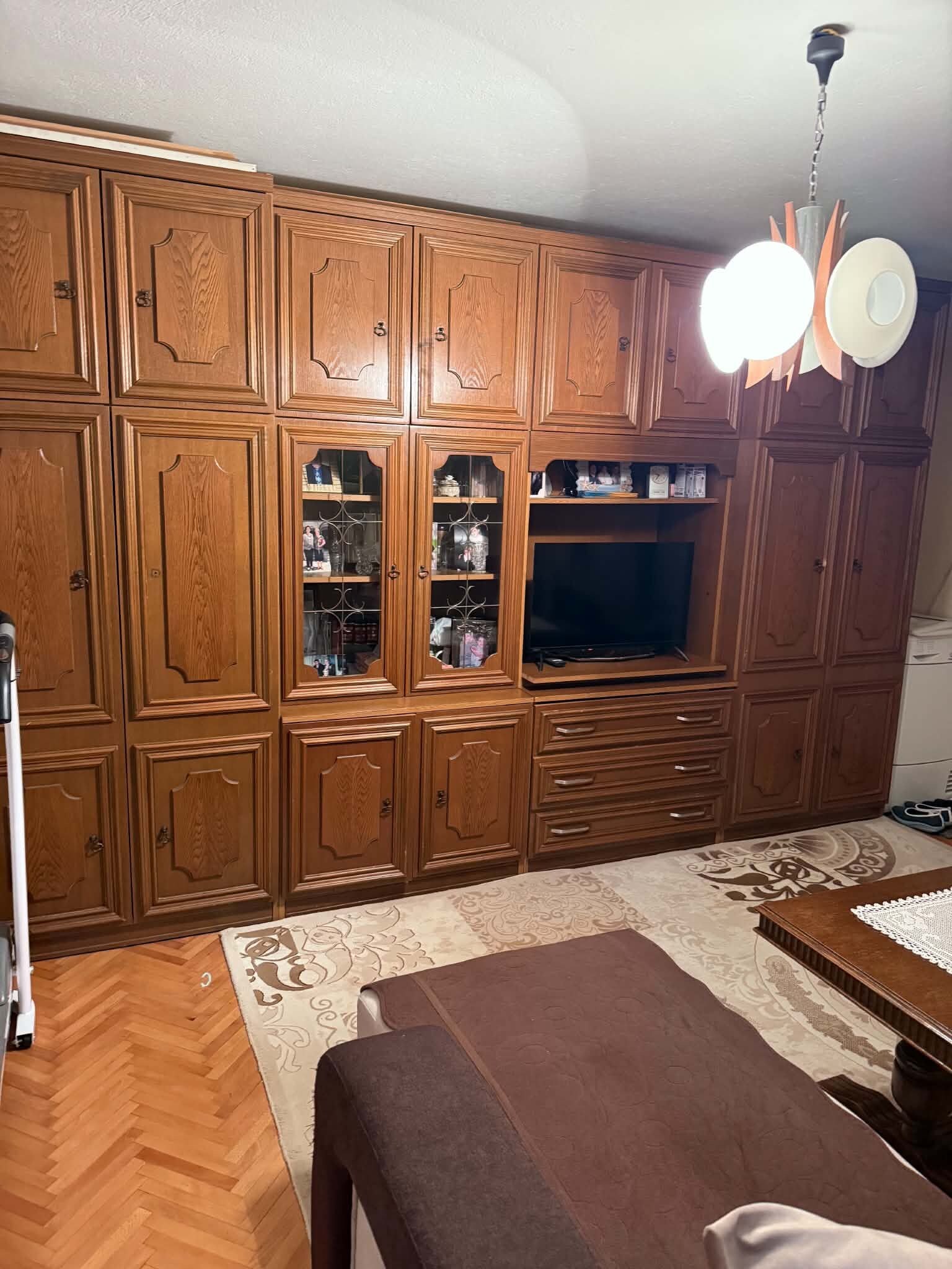 Quarto com armários de madeira, televisão e tapete estampado.