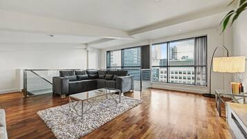 Uma sala de estar moderna com um sofá modular, uma mesa de centro de vidro e uma janela ampla com vista para a cidade.