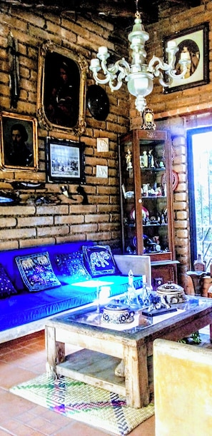 Um quarto com parede de tijolos, um sofá azul, uma mesa de centro de madeira e um candelabro.