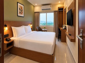 Quarto de hotel com cama, mesa de cabeceira, abajur, aparelho de ar condicionado, televisão e janela com cortinas.