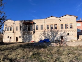 Um edifício de dois andares com fachada de pedra, várias janelas e telhado plano.