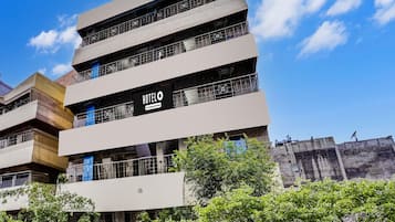 Um hotel com vários andares e um grande letreiro 'HOTEL' na fachada, com varandas e um céu claro ao fundo.