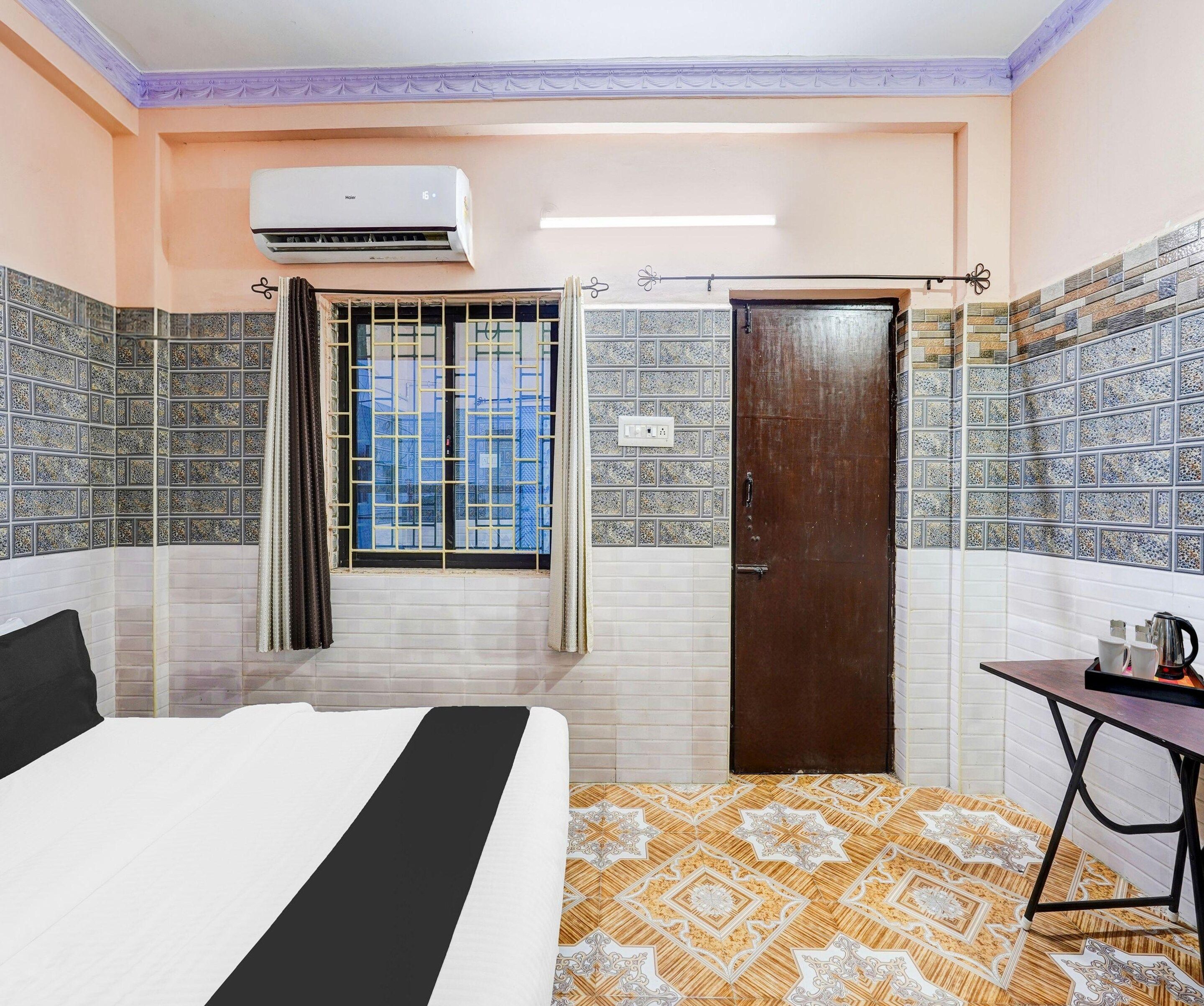 Quarto de hotel com cama, janela com vista, porta e pequena mesa com bandeja.