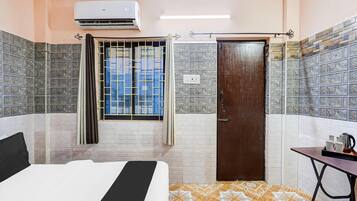 Quarto de hotel com cama, janela com vista, porta e pequena mesa com bandeja.