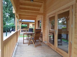 Um deck de madeira com mesa e cadeiras, uma porta de vidro e vista da região ao redor.
