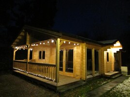 Uma cabana de madeira com varanda coberta e luzes de cordão.