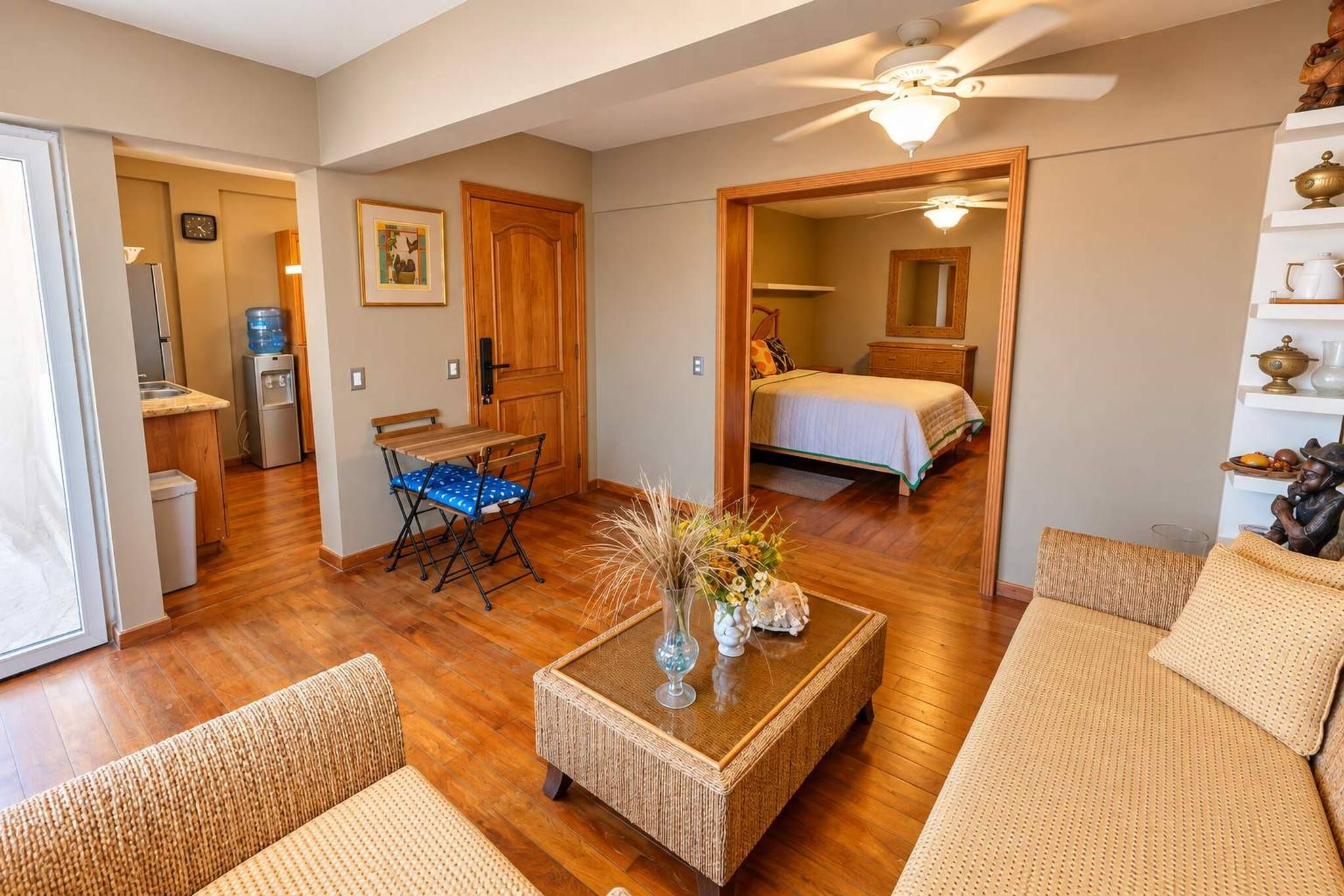 Ampla sala de estar com mesa de jantar, sofá e quarto visível por uma porta aberta.