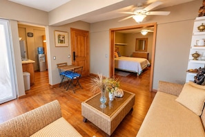 Ampla sala de estar com mesa de jantar, sofá e quarto visível por uma porta aberta.