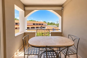 Uma varanda com mesa e cadeiras, vista para edifícios e céu claro.