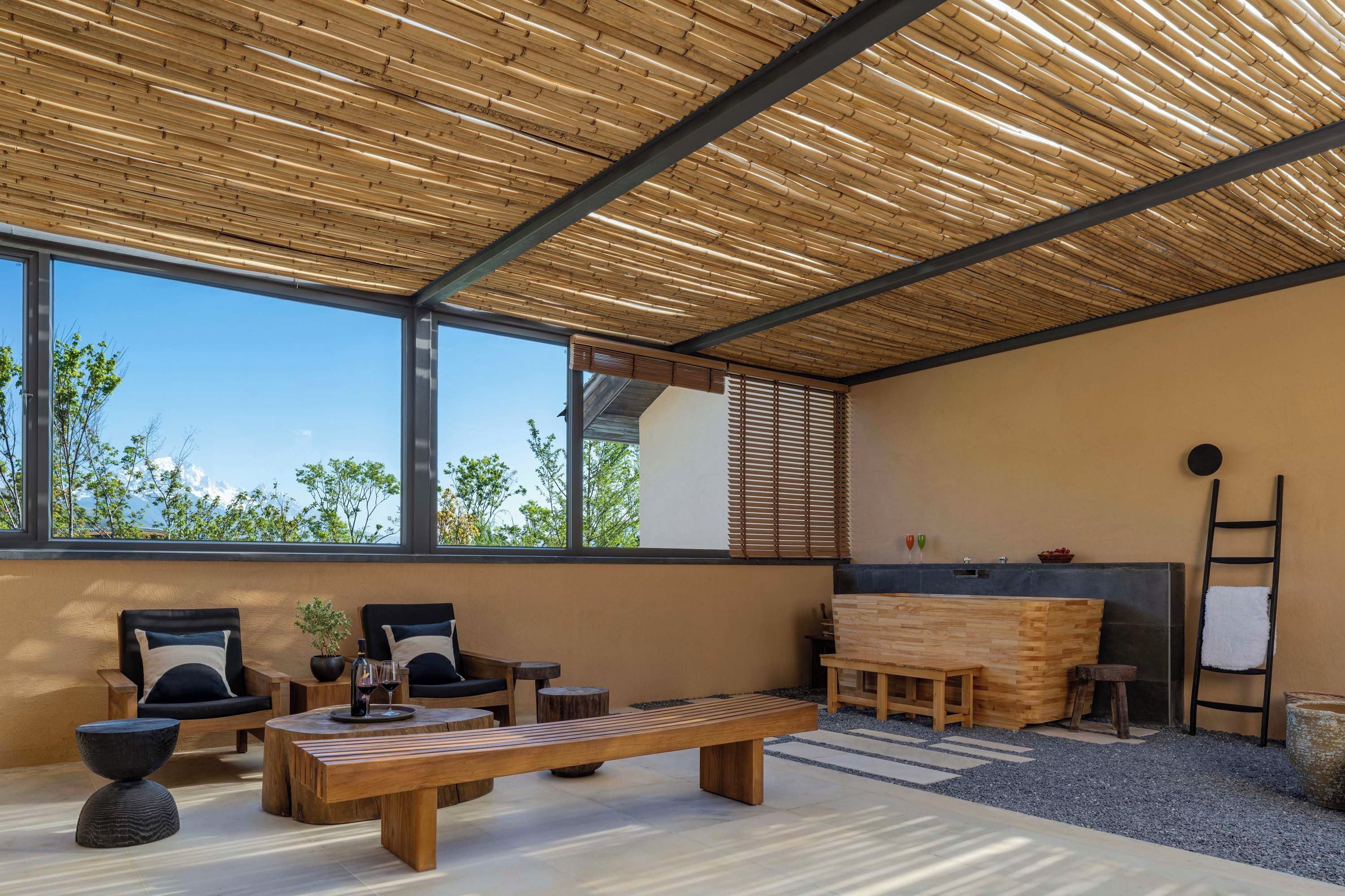 Interior moderno com teto de bambu, janelas amplas e um banco de madeira.