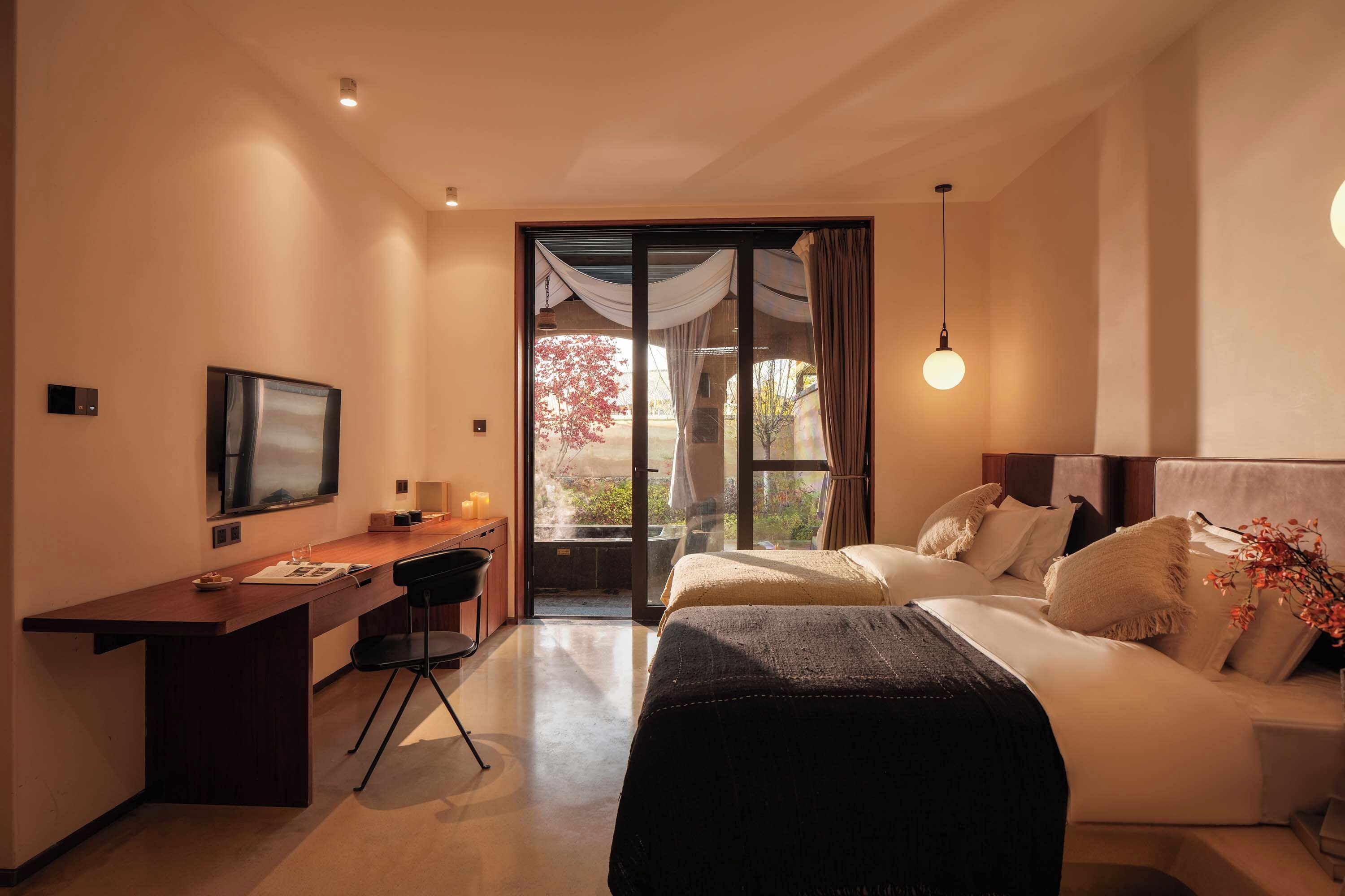 Quarto de hotel com cama, escrivaninha, televisão e vista para o exterior.