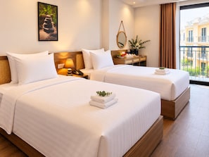 Quarto de hotel com duas camas, uma mesa de cabeceira, abajur, espelho e janela com vista para edifícios.