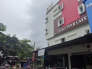 Um edifício de vários andares com uma placa que indica 'Lucky Inn & Cafe' na fachada.