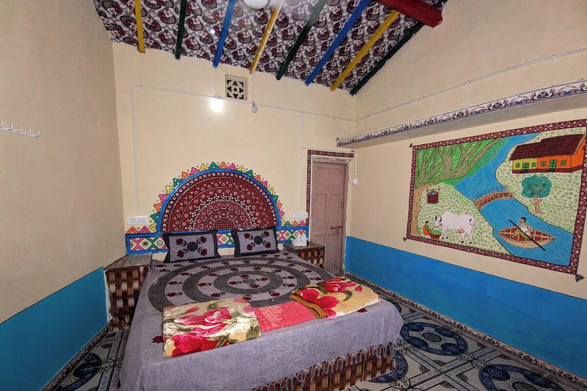 Um quarto com colcha estampada, cabeceira decorativa e painel na parede.