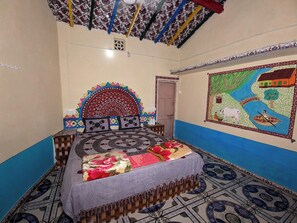 Um quarto com colcha estampada, cabeceira decorativa e painel na parede.