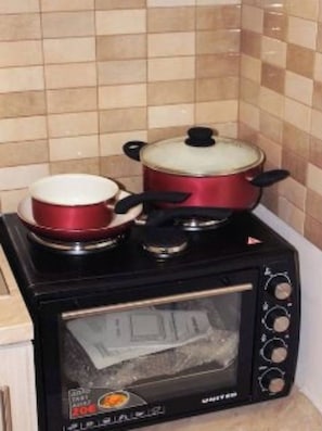 Cozinha com fogão preto, duas panelas e um micro-ondas.