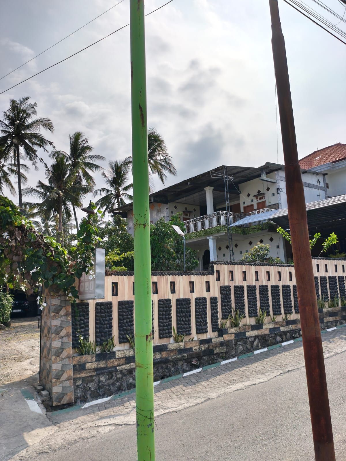 Um edifício residencial com parede de pedra, varanda e palmeiras.