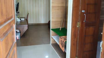 Um corredor com uma porta de madeira, um tapete verde e uma vassoura encostada na parede.