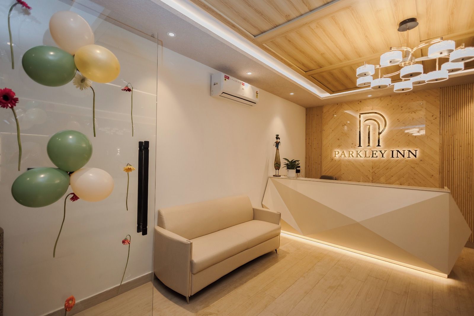 Uma área de recepção com design moderno, incluindo um balcão de atendimento, um sofá e balões decorativos.