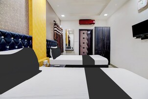 Quarto de hotel com duas camas, guarda-roupa, televisão e espelho.