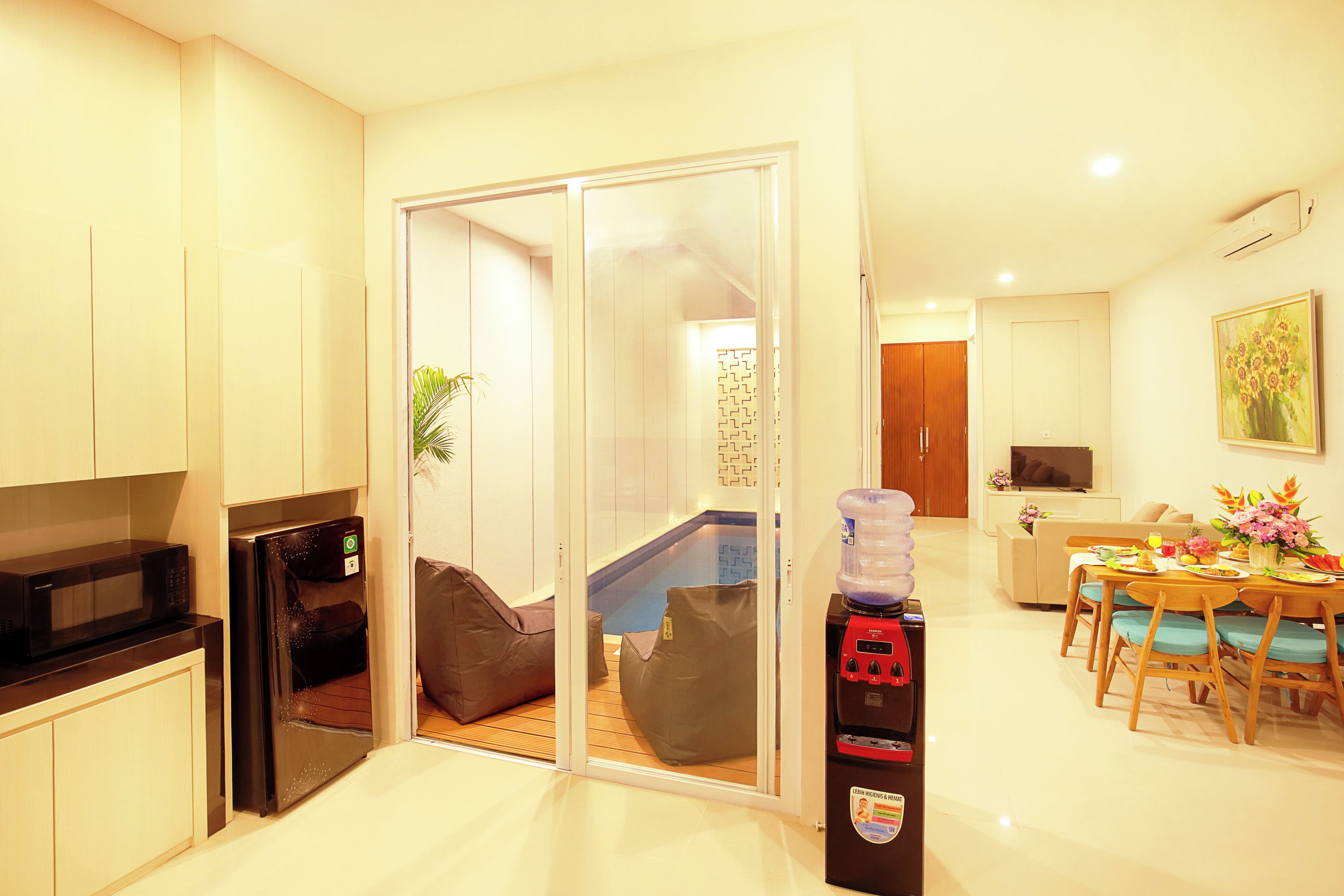 Espaço de estar moderno com cozinha, área de refeições e porta de vidro deslizante que dá para uma varanda.
